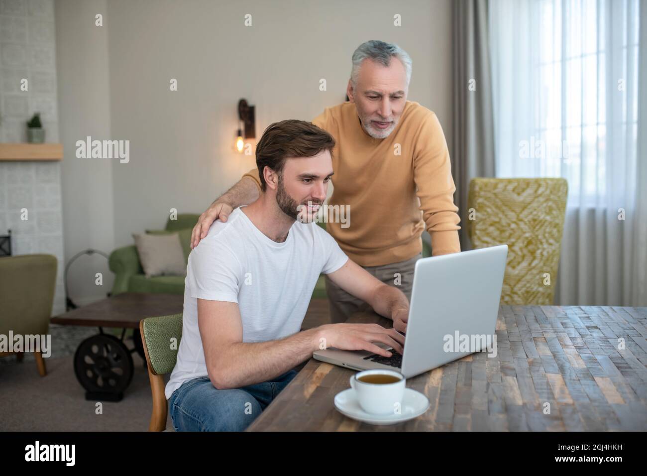 Two men watching something on a laptop and looking involved Stock Photo ...