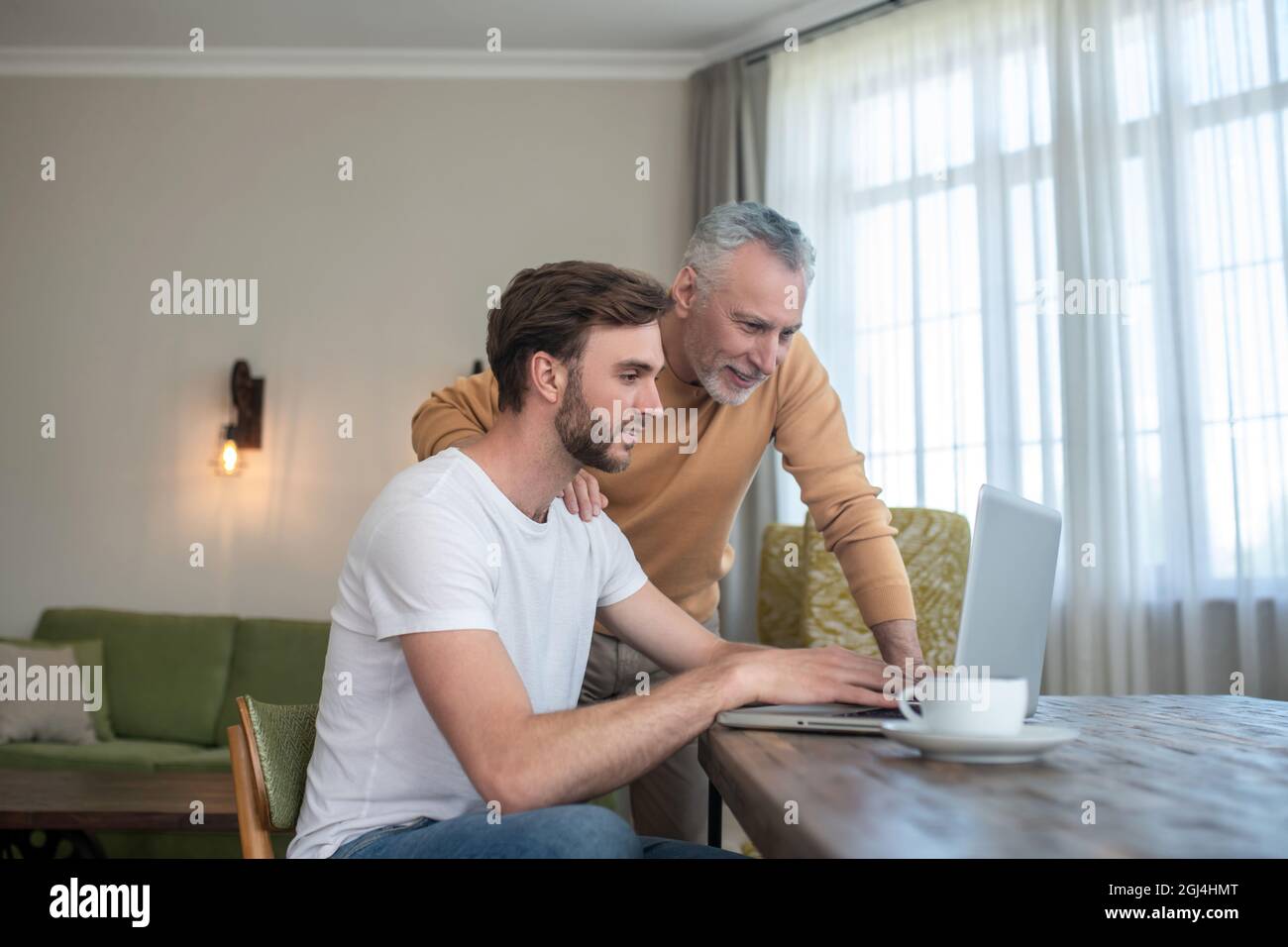 Two men watching something on a laptop and looking involved Stock Photo ...