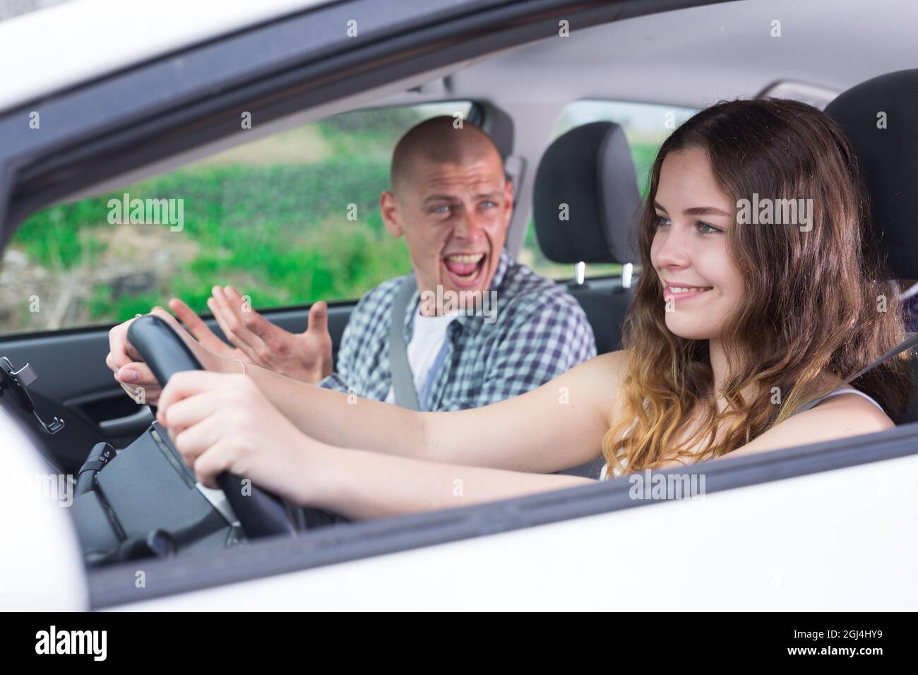 Smiling girl confidently driving car with angry husband Stock Photo - Alamy