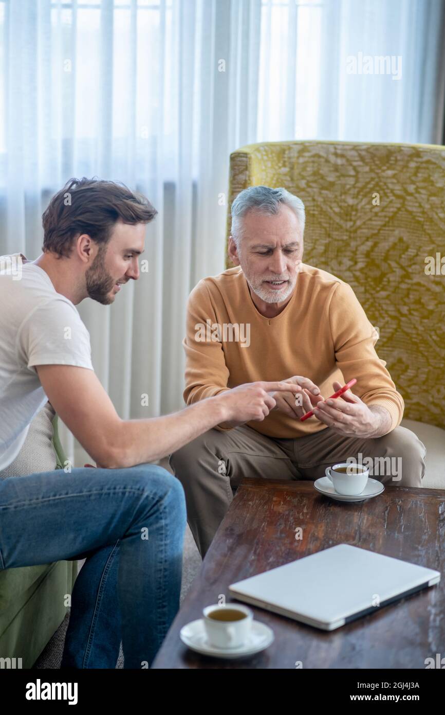 Young man teachng his dad how to use a new smartphone Stock Photo - Alamy