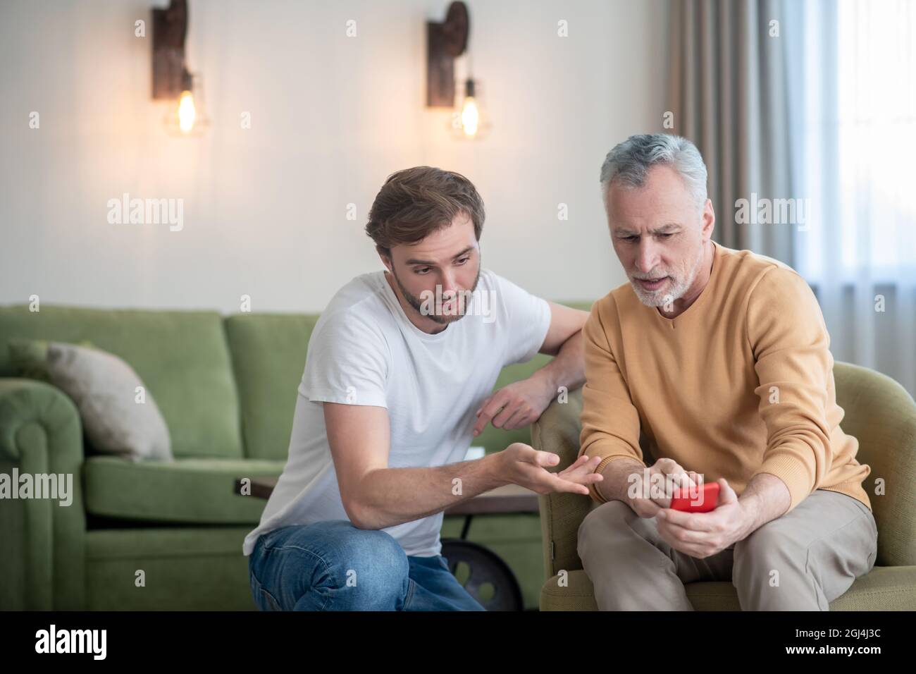 Young man teachng his dad how to use a new smartphone Stock Photo - Alamy