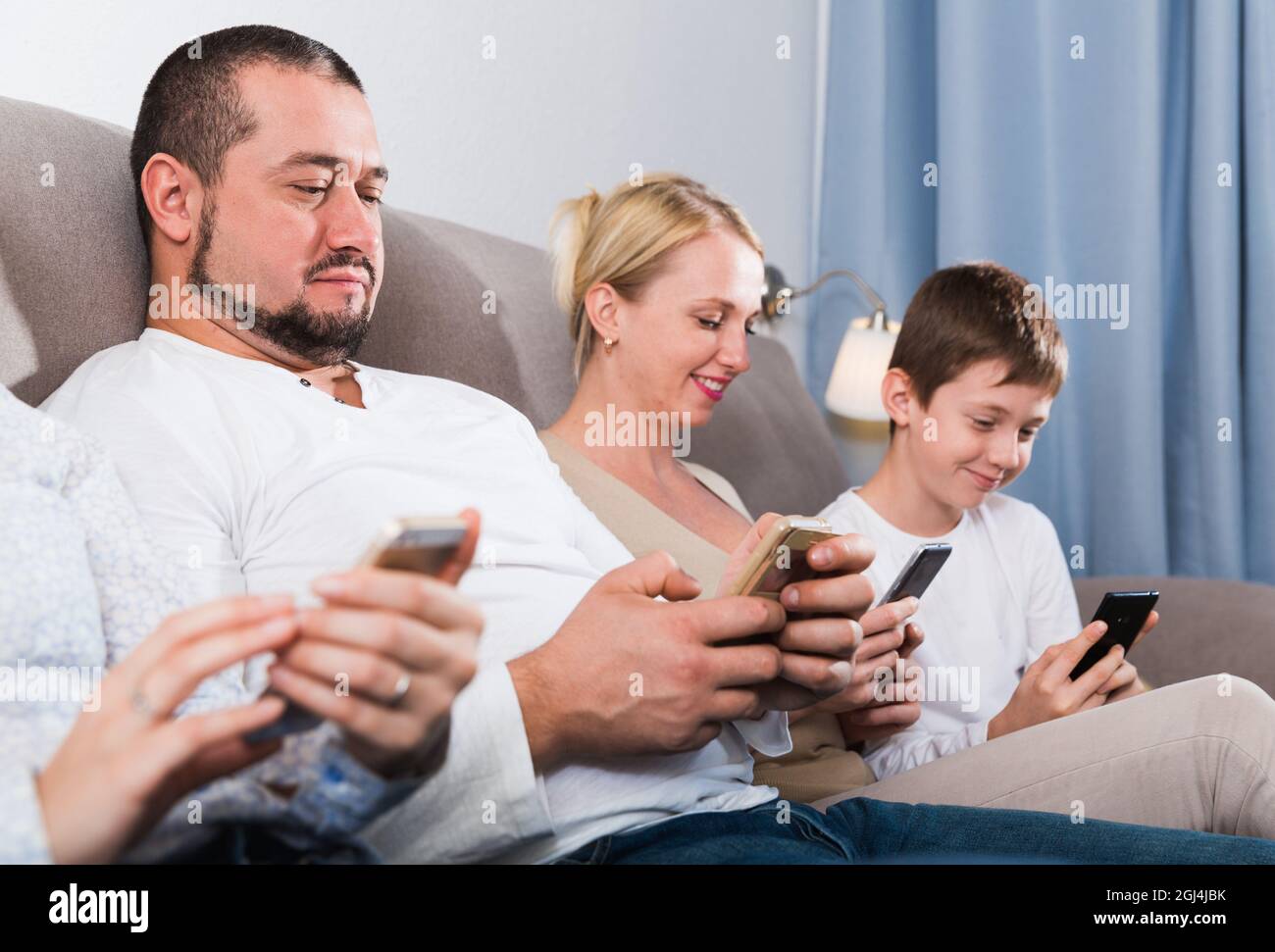 Parents and son using phones at home Stock Photo - Alamy