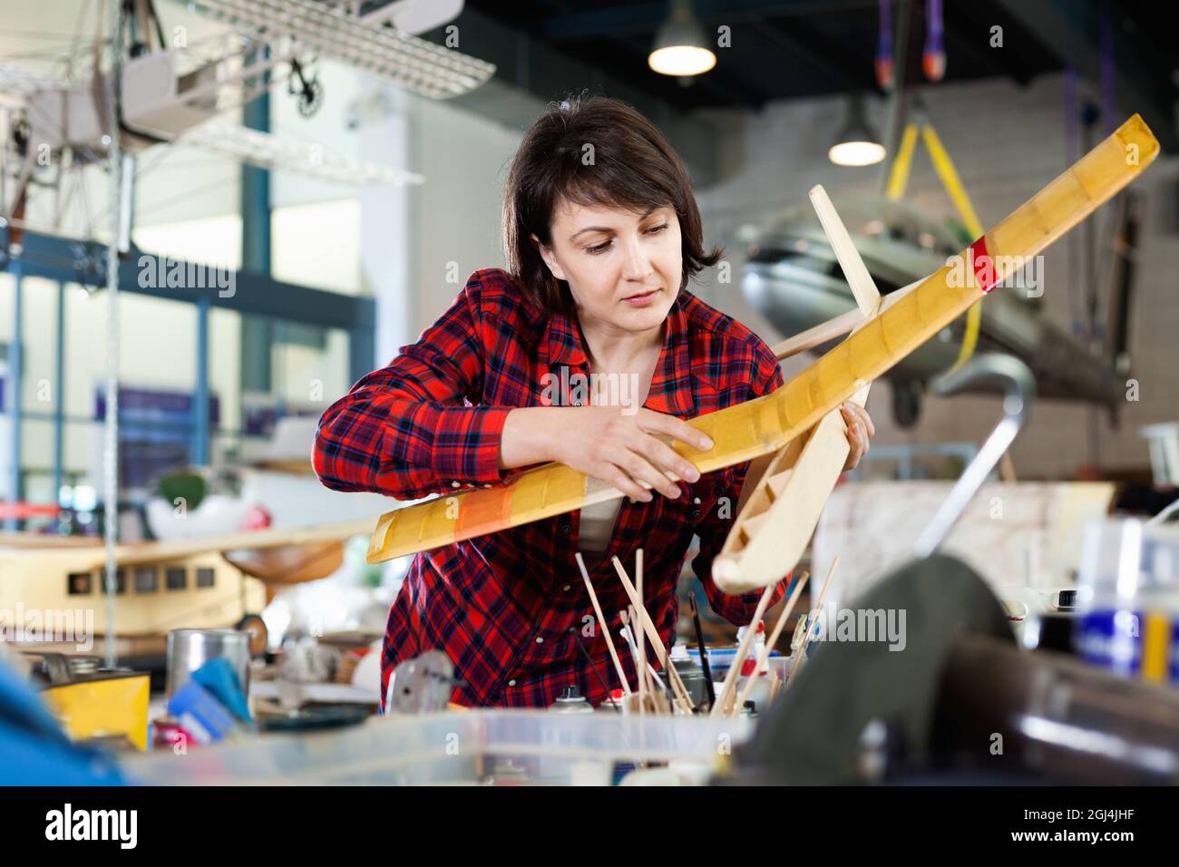 Female aircraft enthusiast engaged in creating plane models in workshop ...