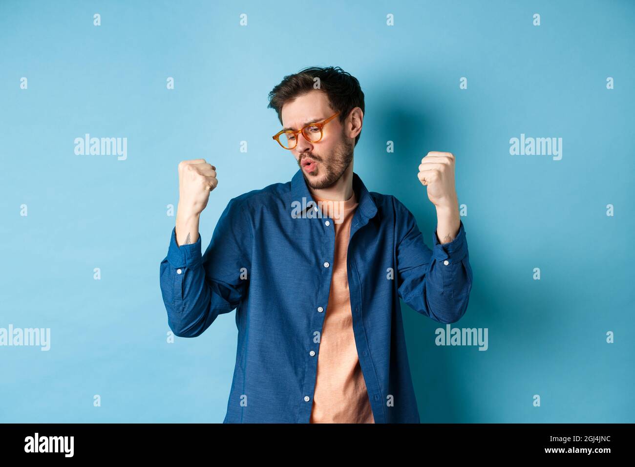 Successful guy dancing and triumphing in new eyewear, raising hands up ...