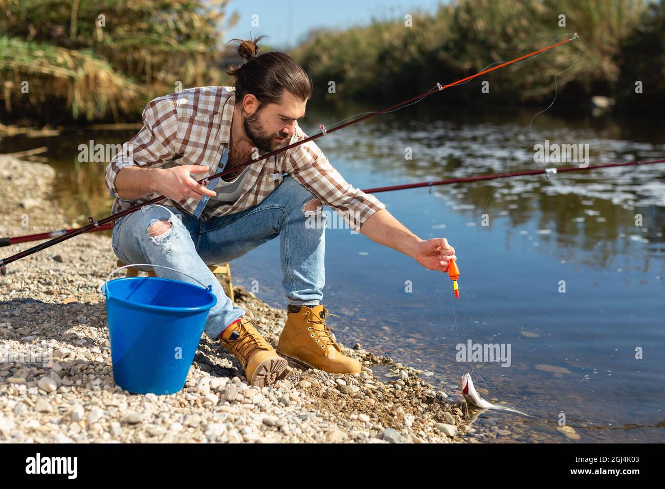 Positive fisherman holding catch freshwater fish in hands Stock Photo ...