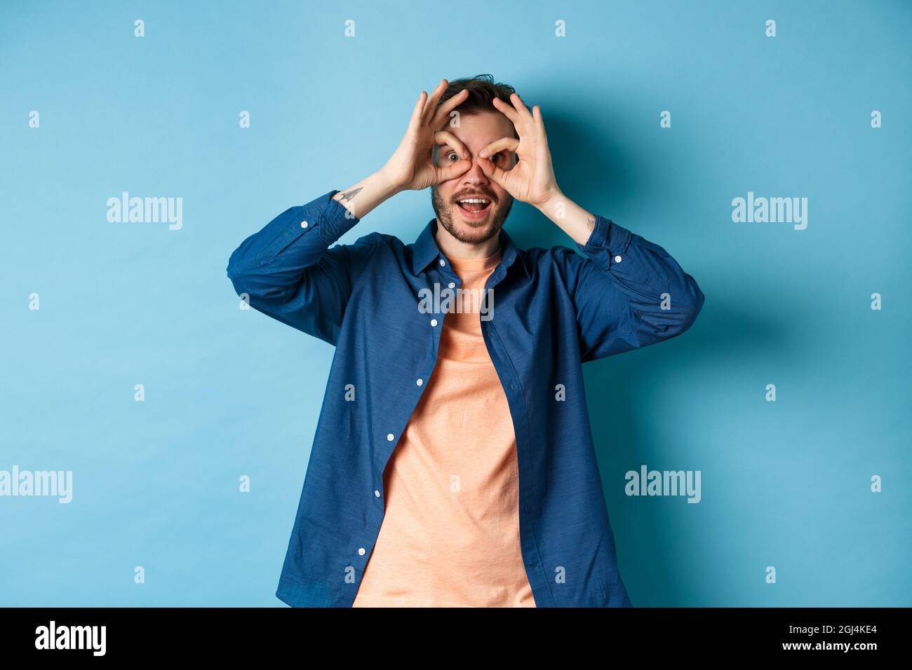 Funny caucasian guy looking through hand binoculars and smiling ...