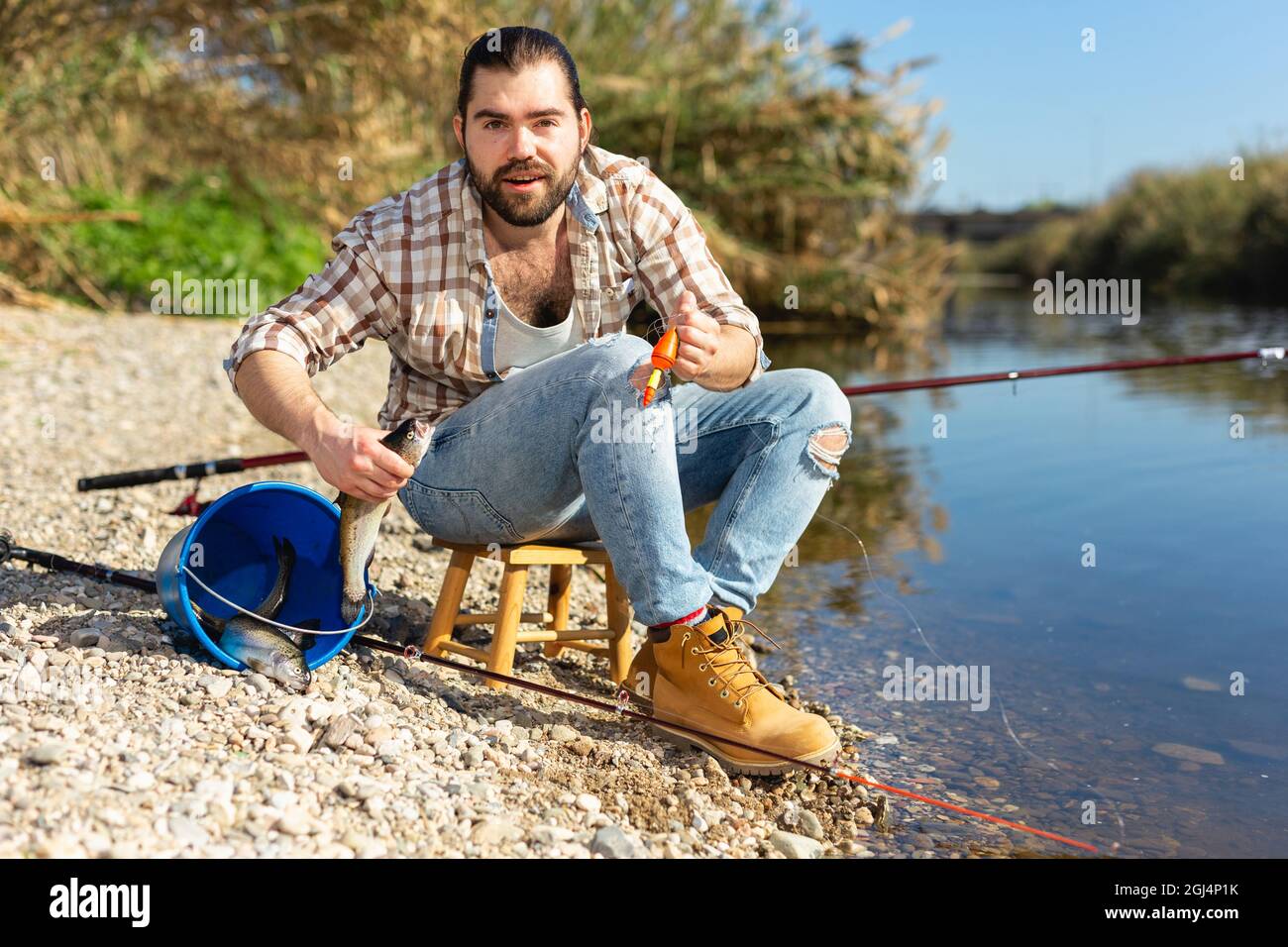 Positive fisherman holding catch freshwater fish in hands Stock Photo ...