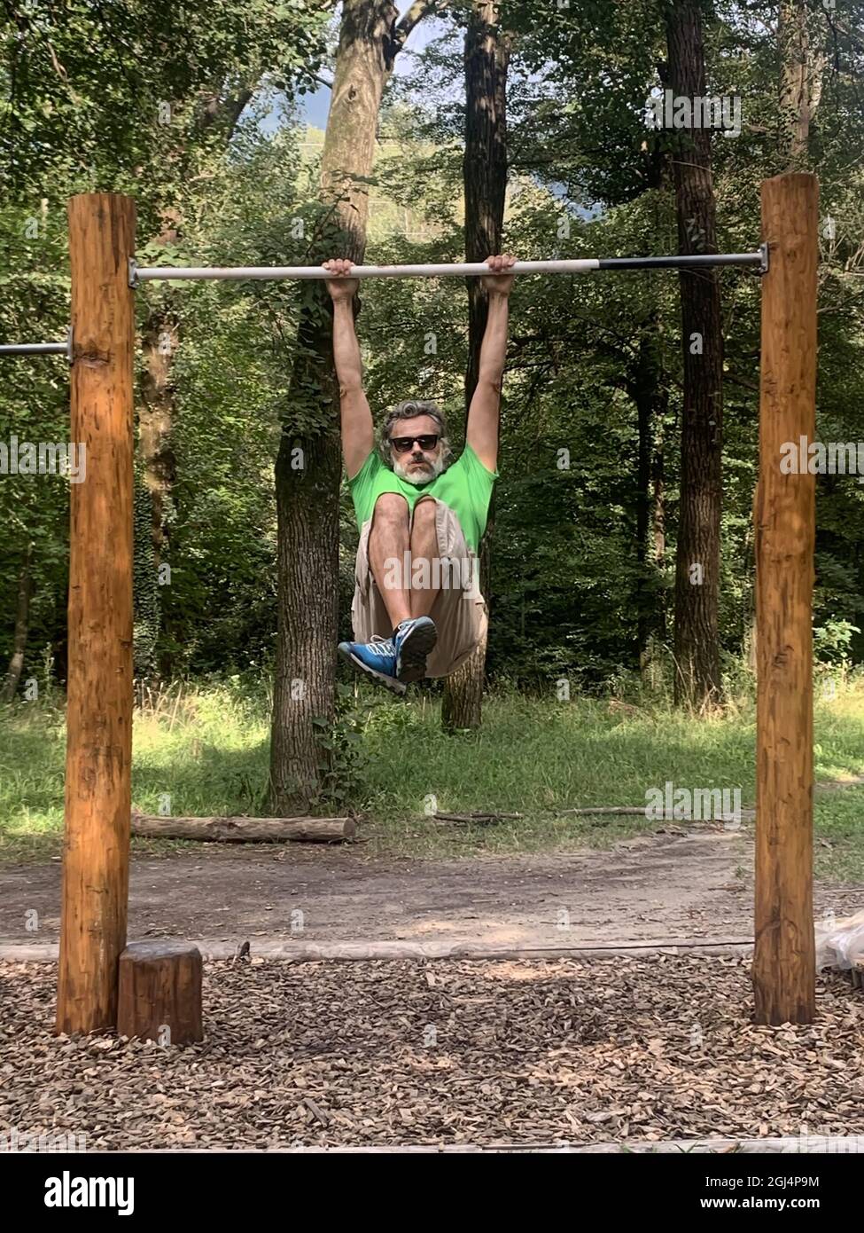 Vertical shot of a strong elderly Caucasian man doing pull-ups on a ...