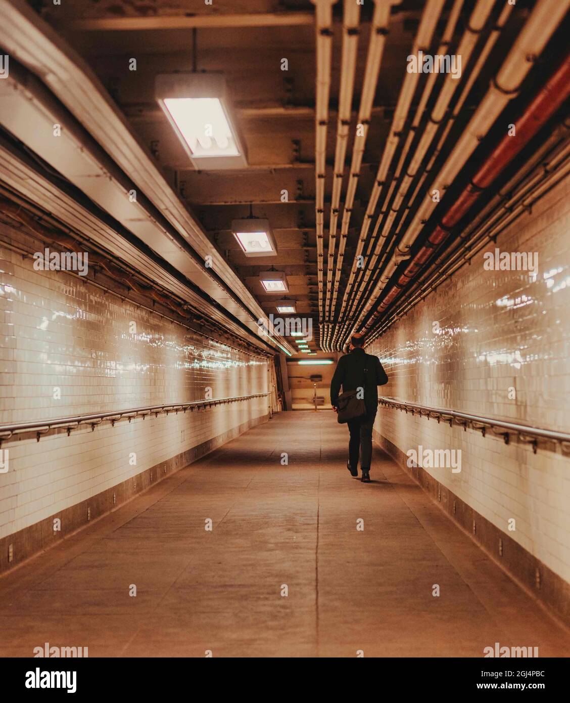 Back view of a male walking down the shiny underground tunnel Stock ...