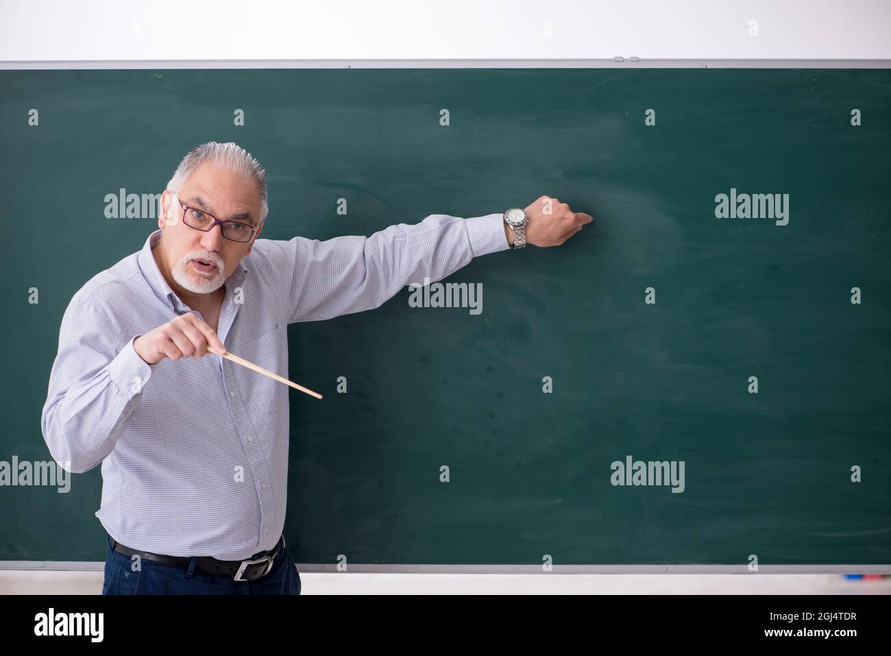 Old teacher in front of green board Stock Photo - Alamy