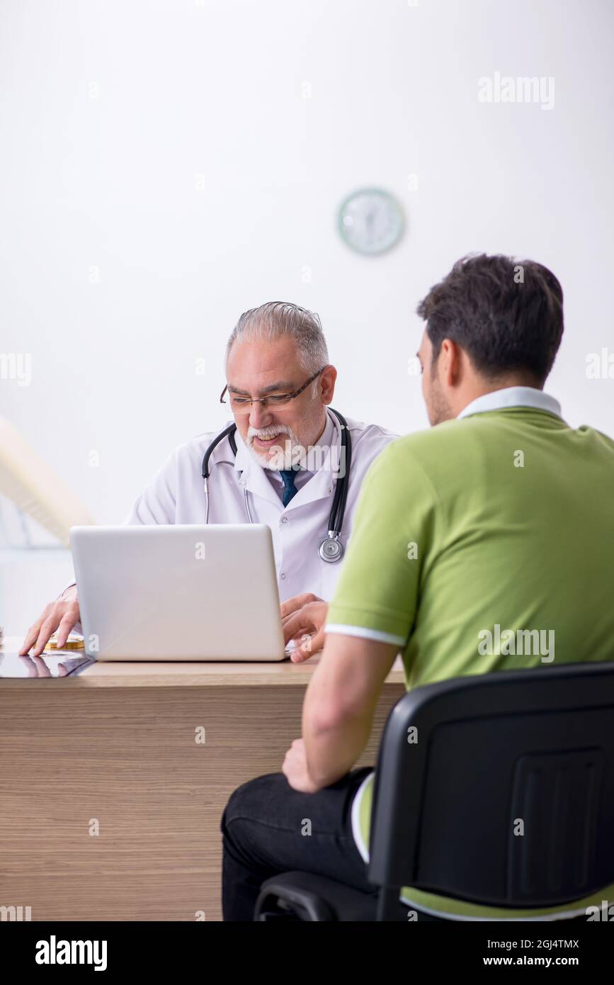 Young man visiting old doctor Stock Photo - Alamy