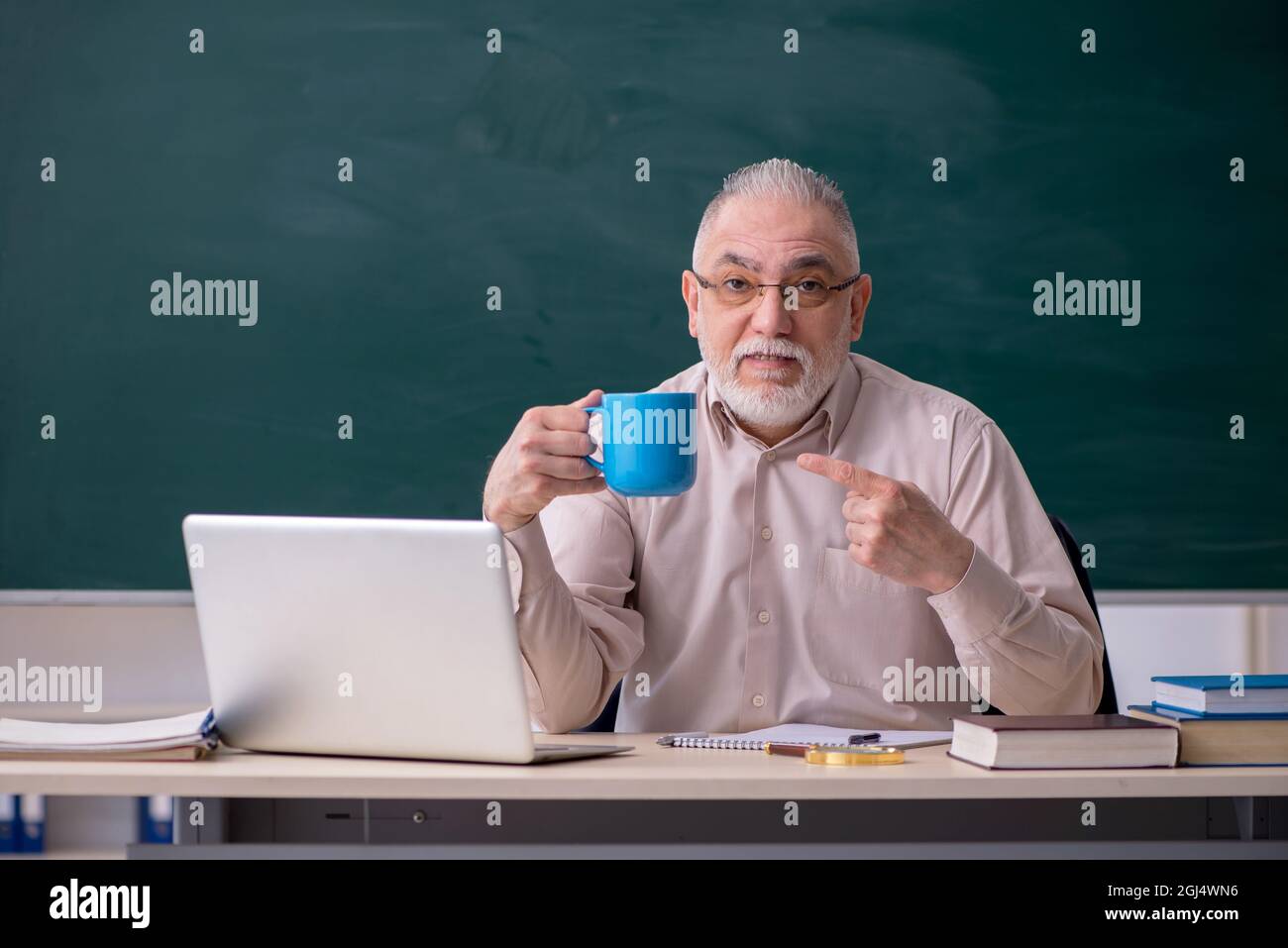 Old teacher drinking coffee in the classroom Stock Photo - Alamy