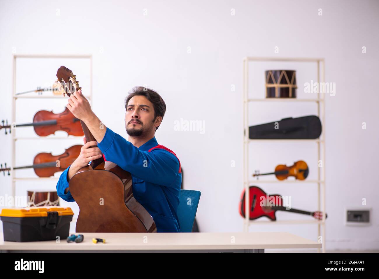 Young repairman repairing musical instruments at workplace Stock Photo ...