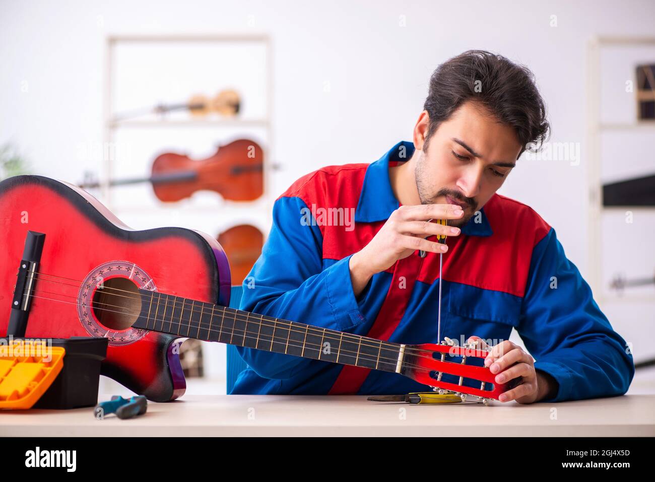 Young repairman repairing musical instruments at workplace Stock Photo ...
