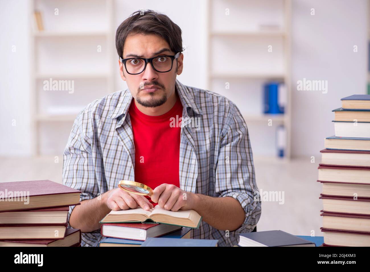 Young student and too many books in the classroom Stock Photo - Alamy