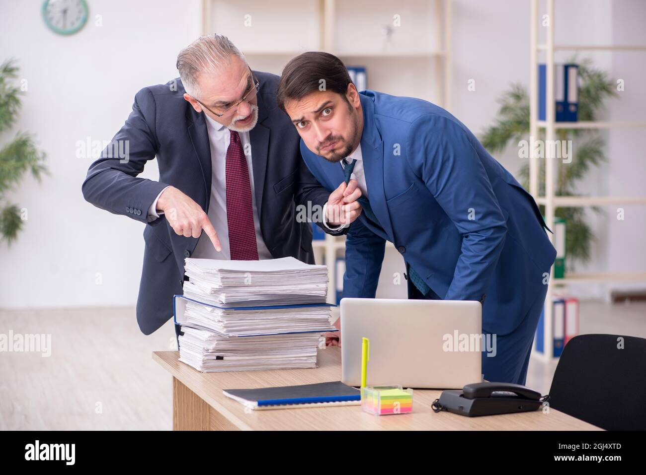 Old boss and young employee in bullying concept Stock Photo - Alamy