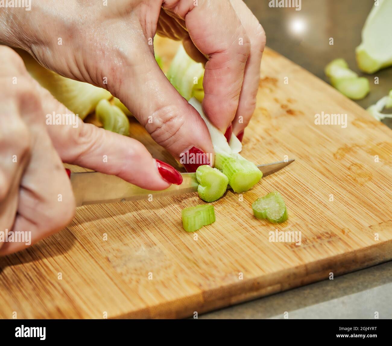 Chef cuts the fennel according to the cooking recipe on wooden board in ...