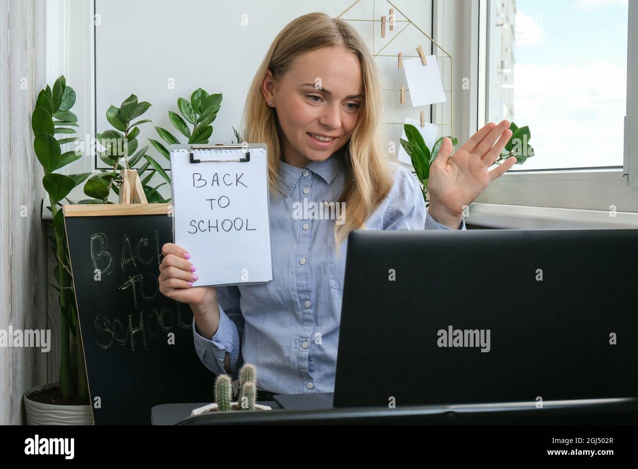 Young female teacher sitting at desk and using laptop at home. e ...