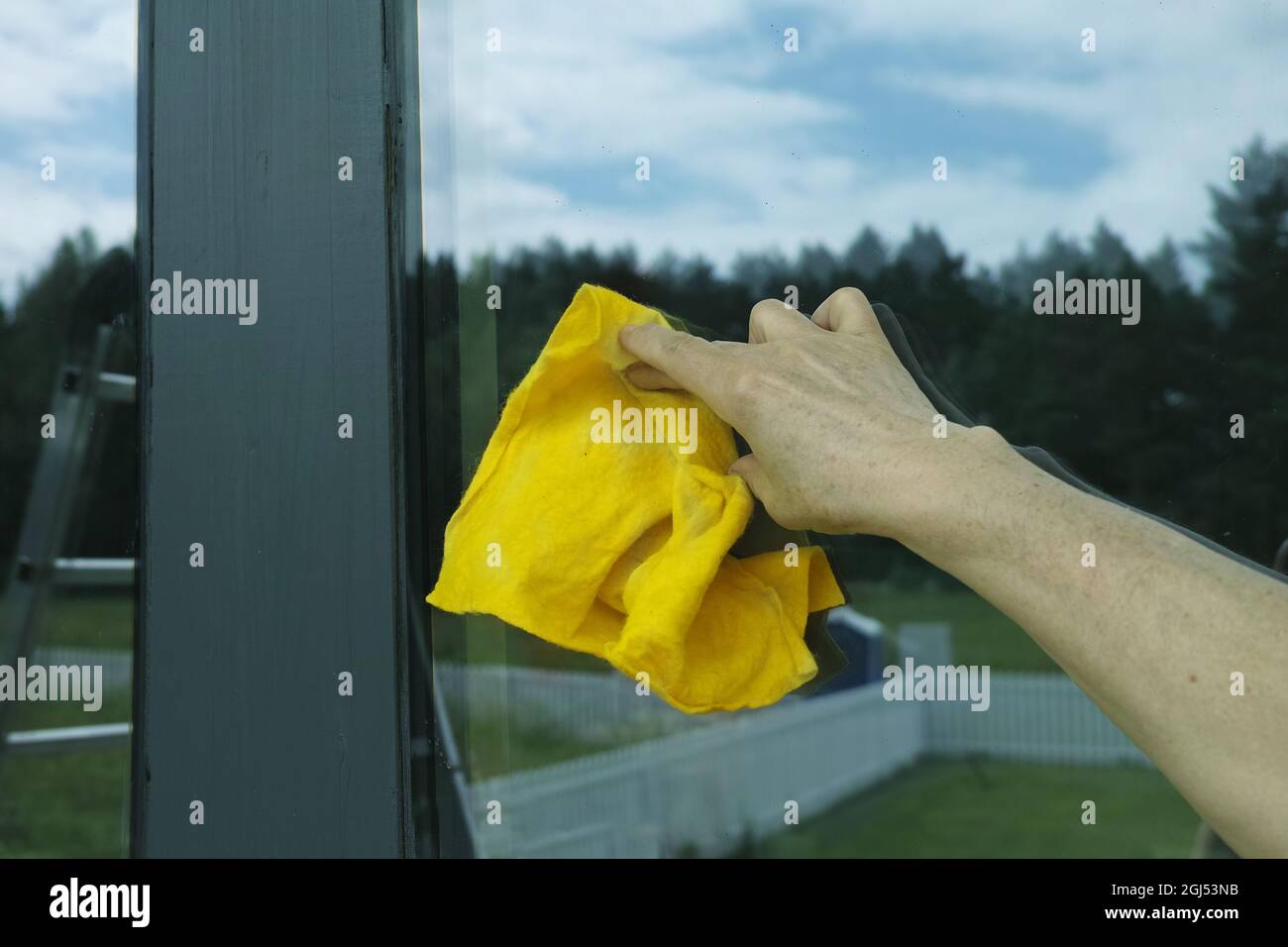 A male hand with a cloth washing window with stained glass outside a ...