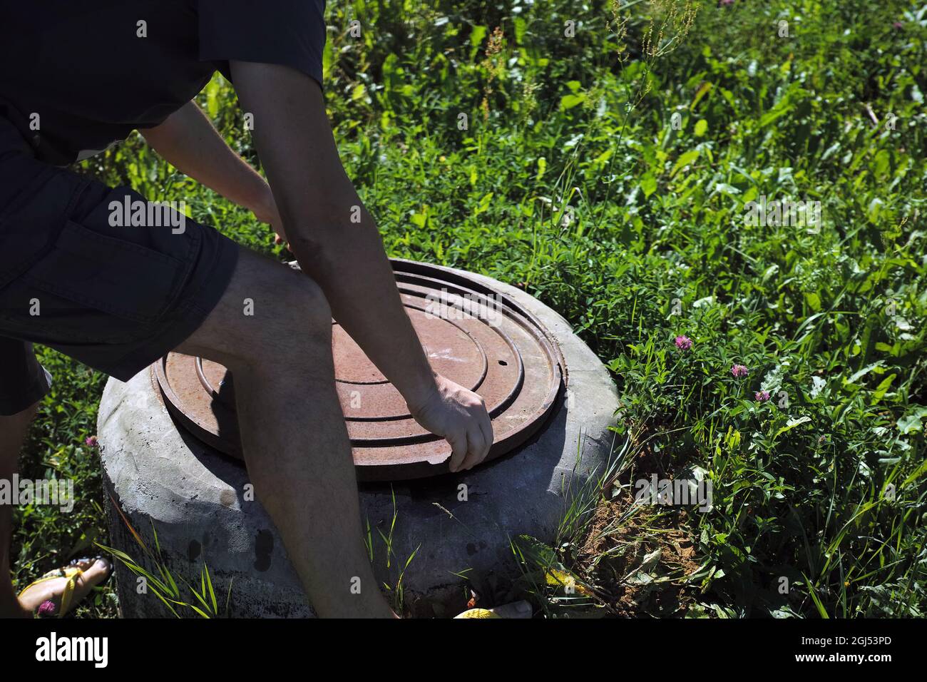 A man about to inspect a manhole, outdoor summertime shot Stock Photo ...