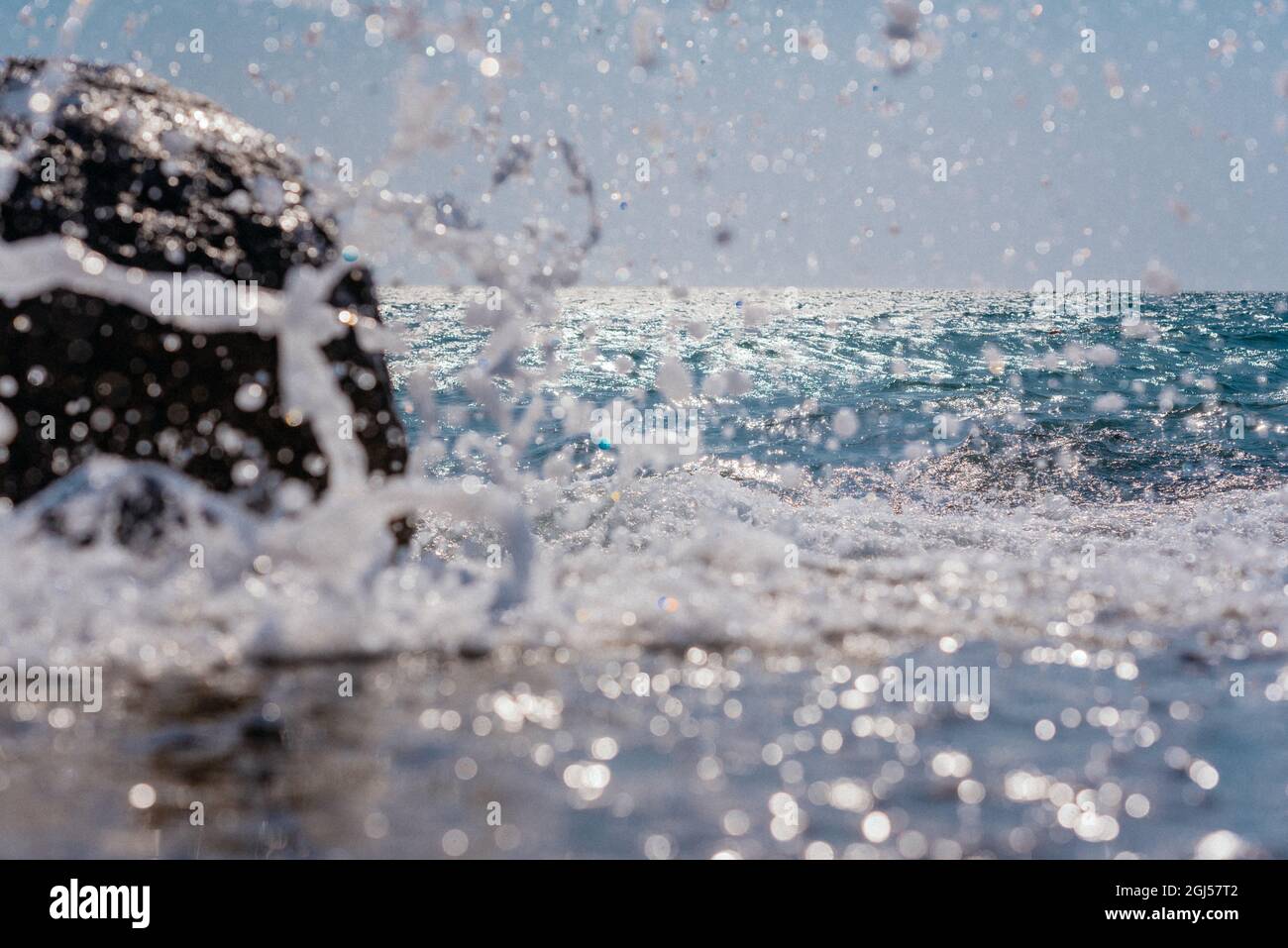 A heavy sea wave breaks into white foam splashes on the shore, big wave ...