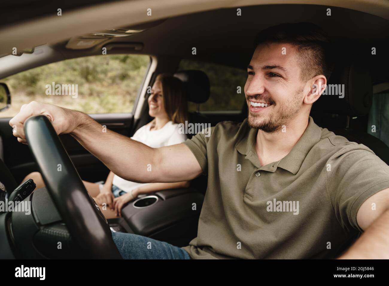 Beautiful young couple sitting on front passenger seats and driving a ...