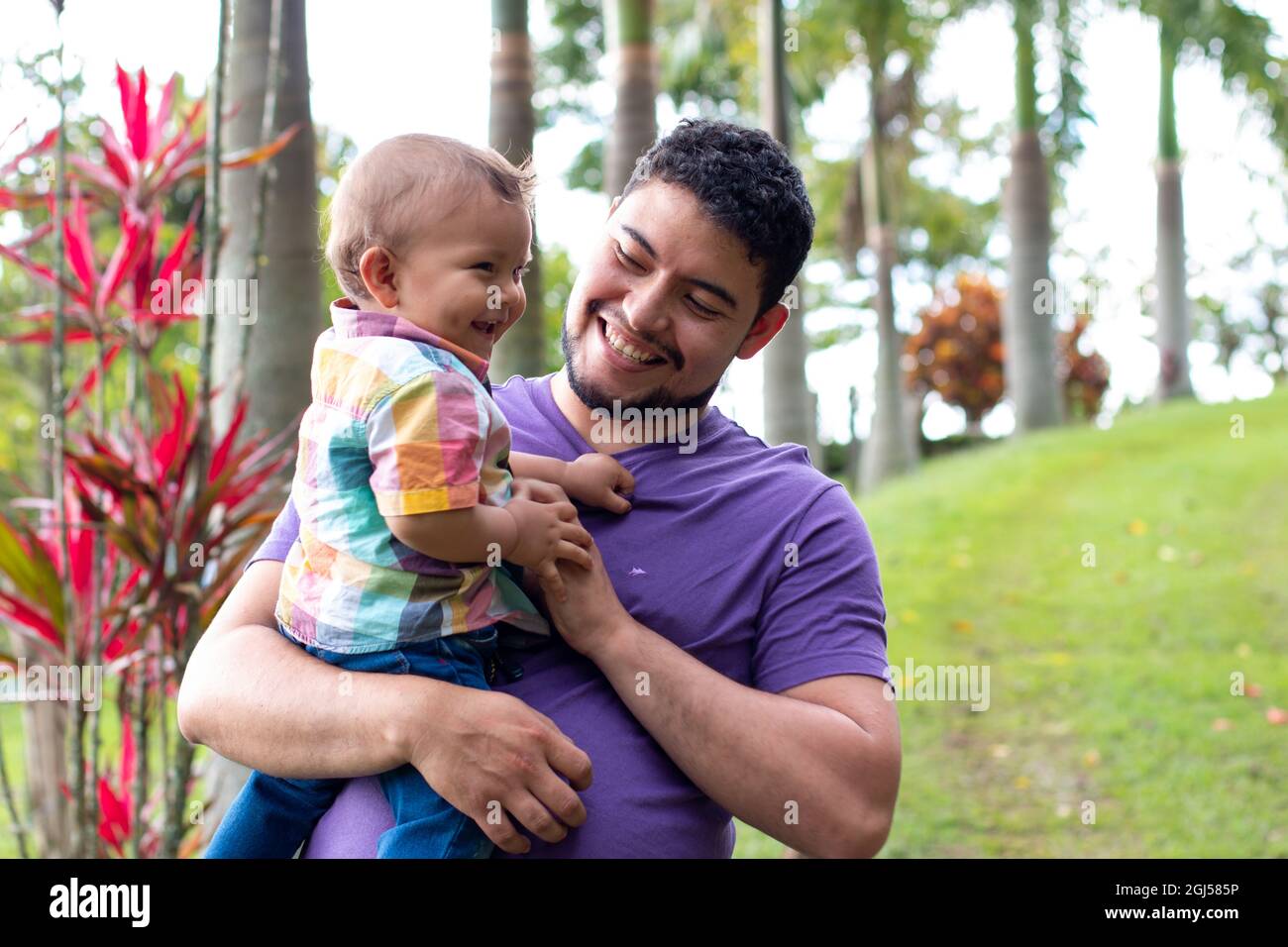 Cheerful young Colombian father holding his child in the park Stock ...