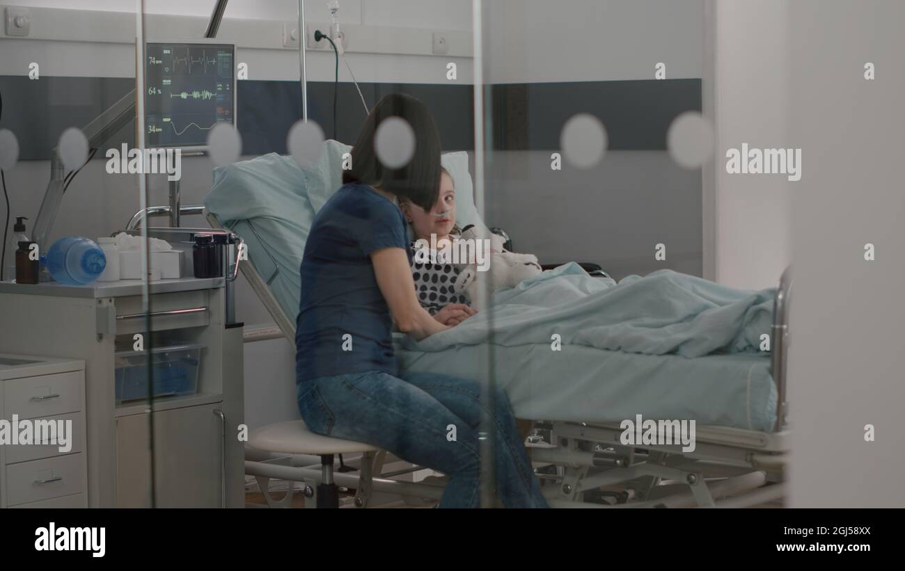 Hospitalized sick child resting in bed after suffering medical surgery ...