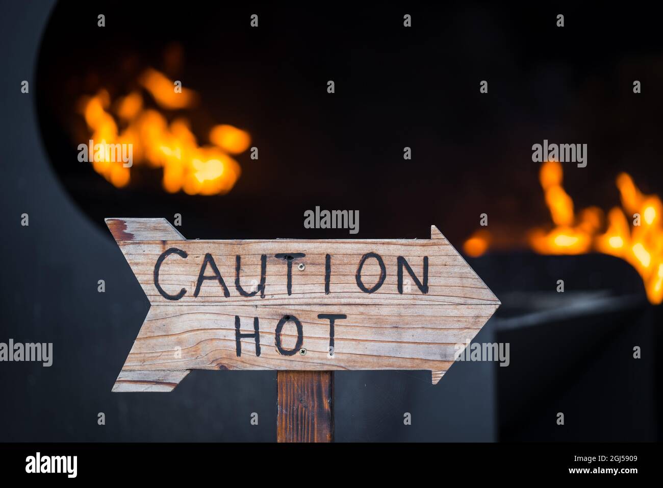 Caution warning hot wooden arrow sign with orange fire and flames ...