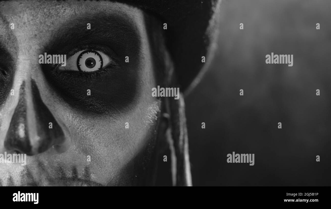 Close-up shot of face in skeleton Halloween makeup opening eyes with ...