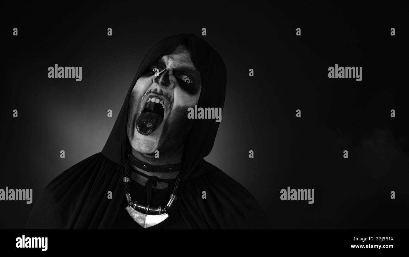 Creepy man with skeleton makeup in hood making angry faces, looking at ...