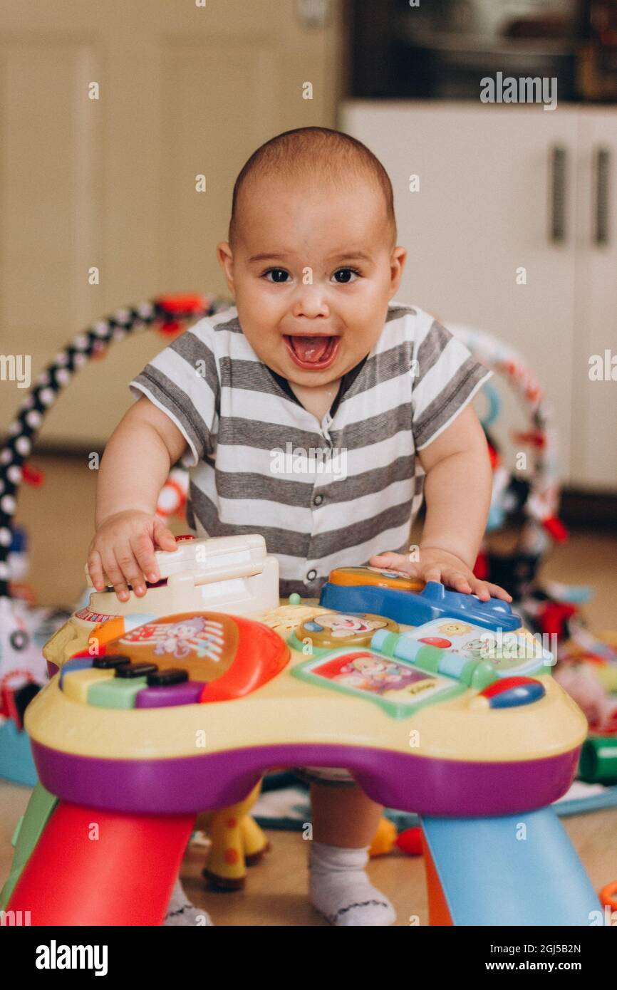 Cute chubby baby stands and plays with children's music table. Lots of ...