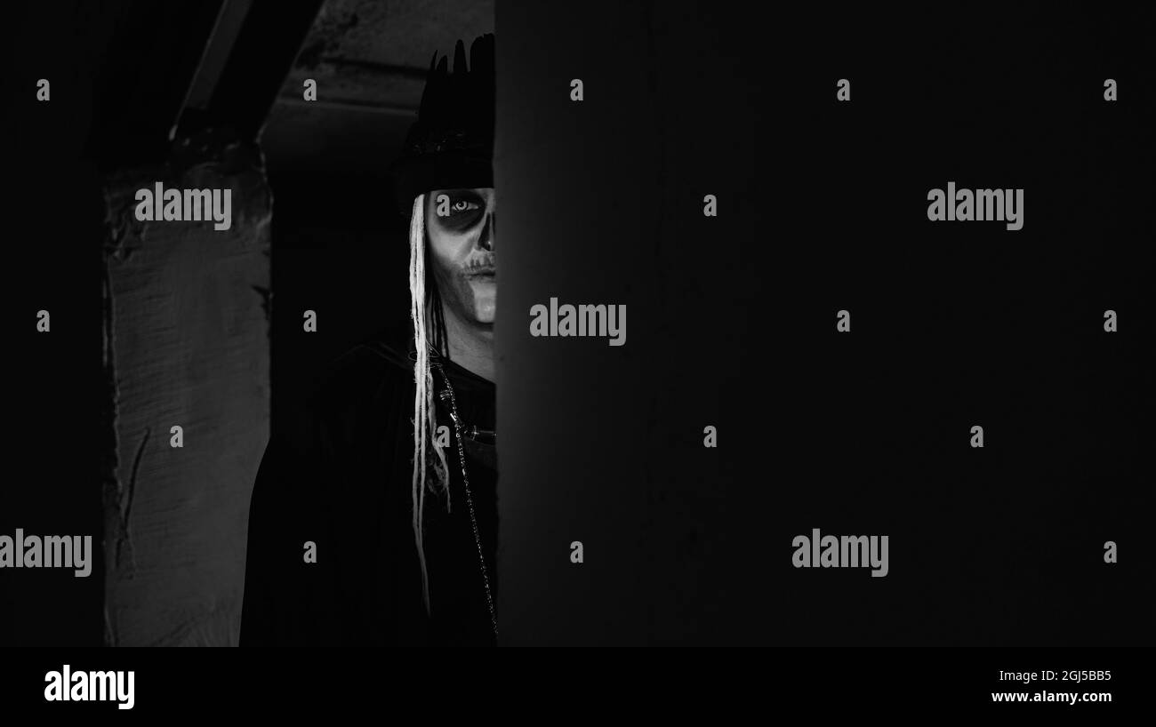 Sinister man with Halloween skeleton makeup slowly appears from dark ...