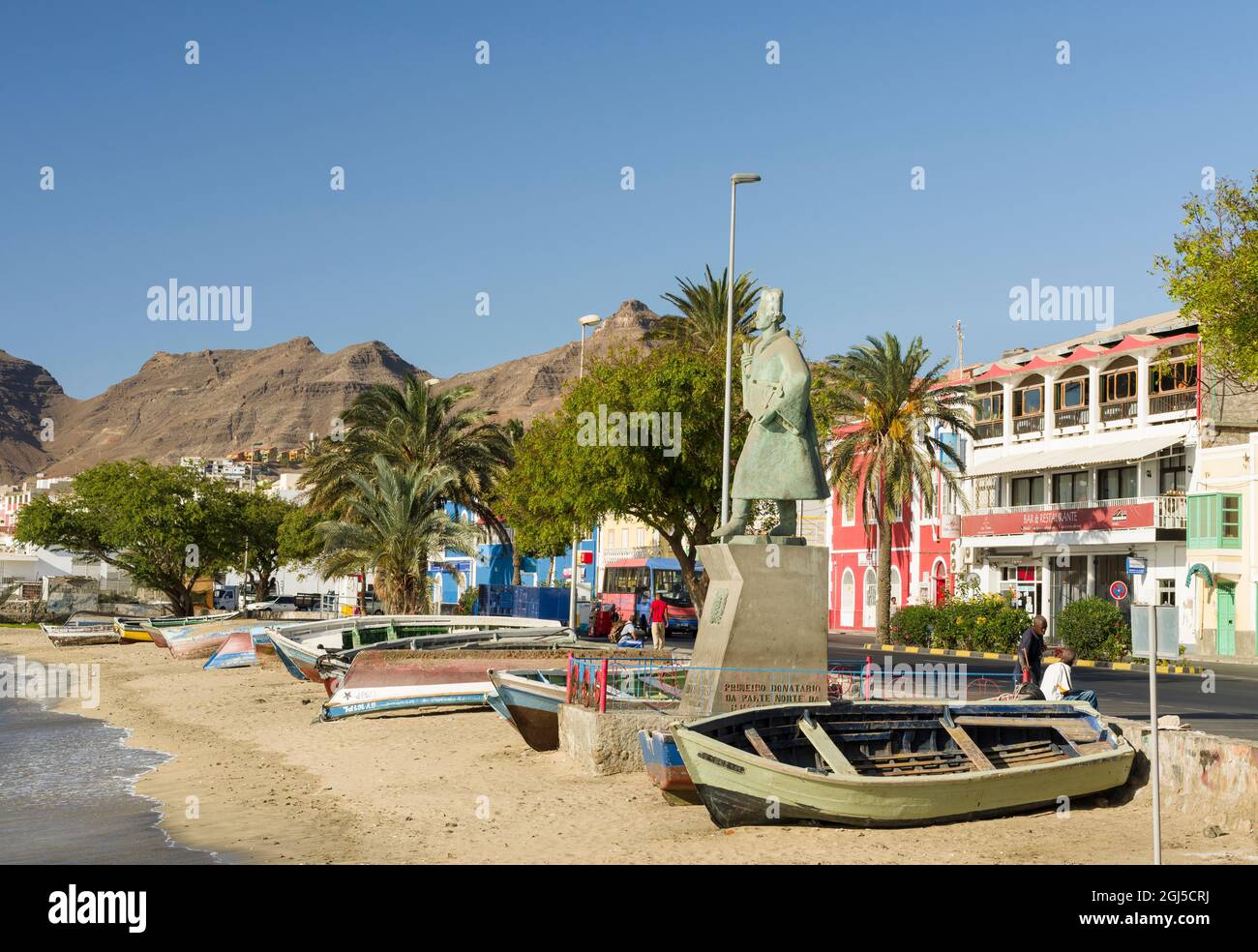 Traditional fishing boats on the beach of the harbor and statue of ...