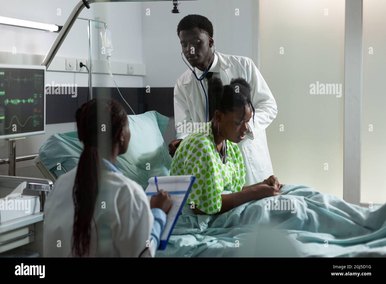 Team of african ethnicity doctors examining patient in hospital ward ...