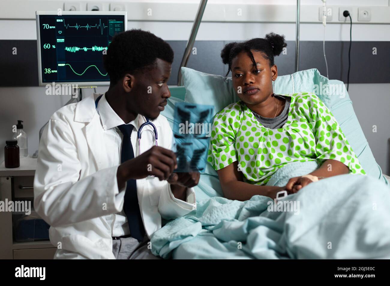 African american doctor and patient looking at x ray in hospital ward ...