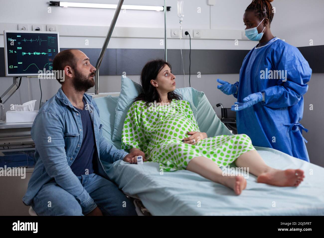 Woman with pregnancy talking to obstetrics nurse while sitting in ...