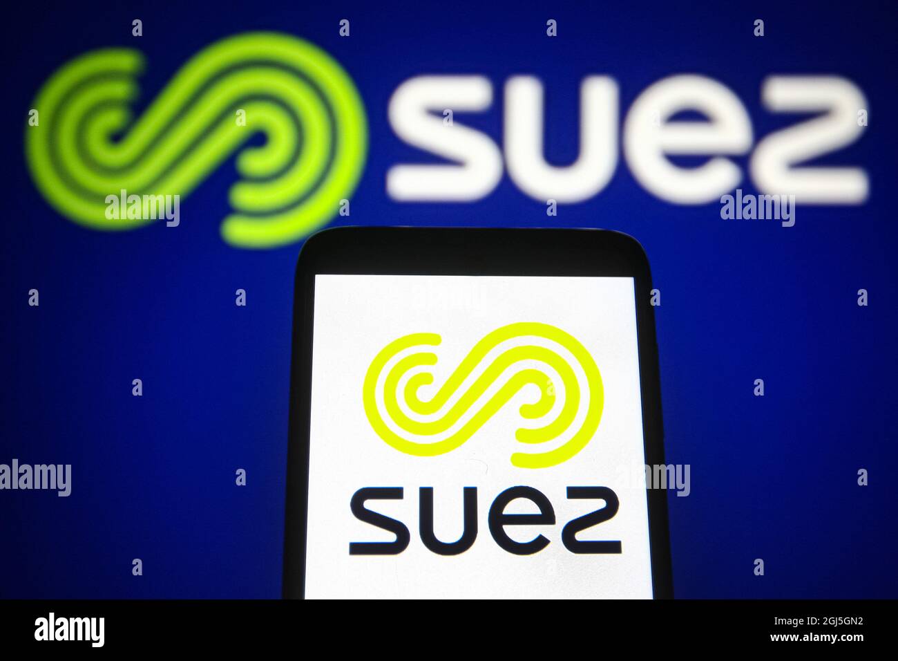 In this photo illustration, SUEZ logo is seen on a smartphone and a pc ...