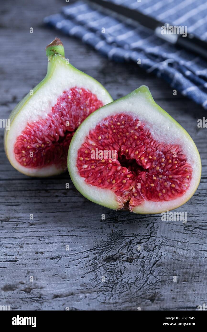 A green fig cut in half on rustic background Stock Photo - Alamy