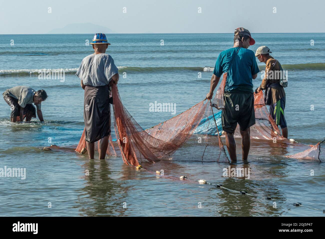 Fisherman pulling the fishing net out of the sea Stock Photo - Alamy