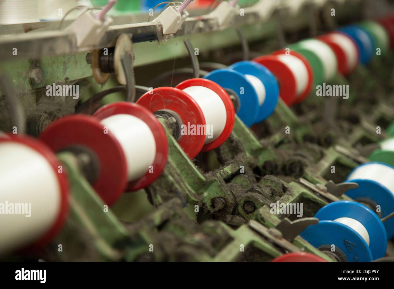 Industrial machines making cotton threads on spools in fabric factory ...