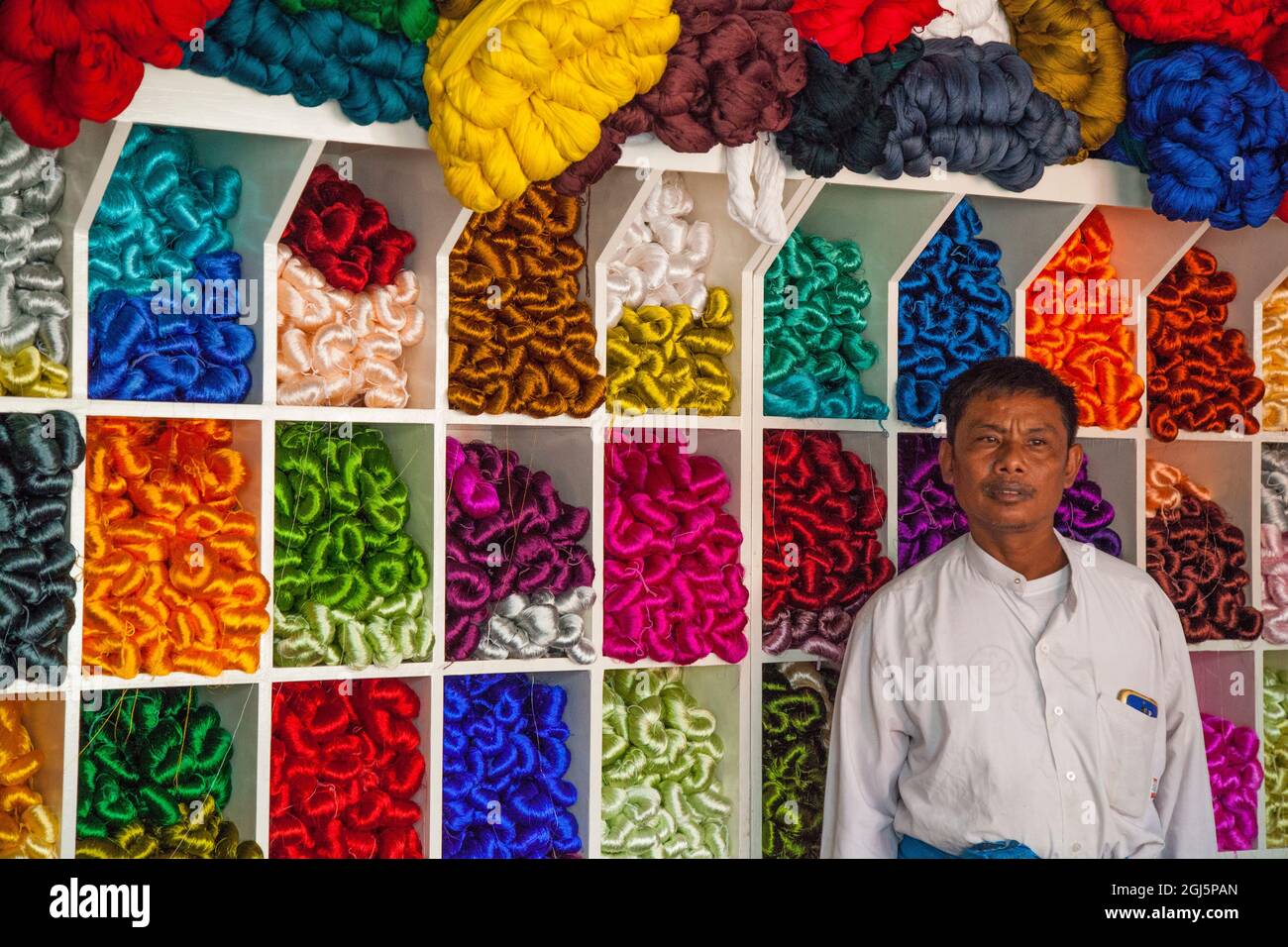 Local Burmese worker with wall of threads in fabric factory shop in ...