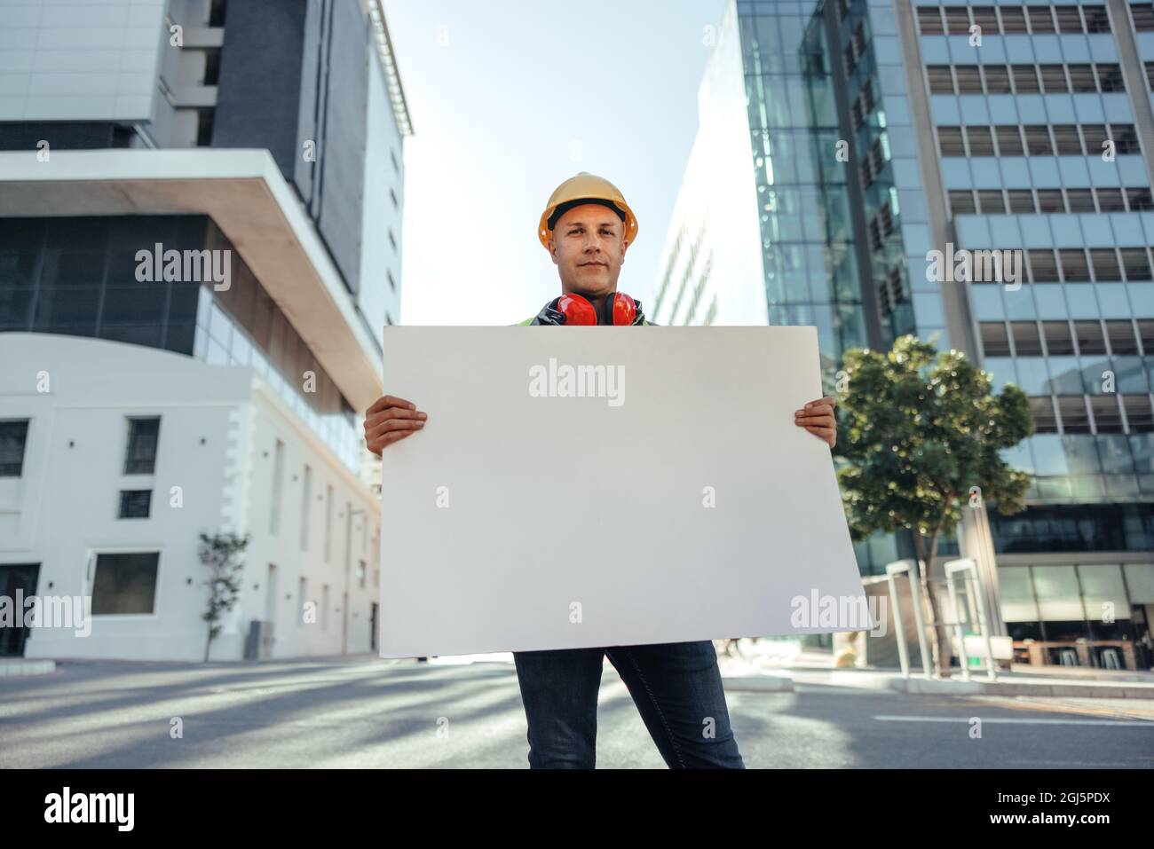 Blue collar worker looking at the camera while holding a blank placard ...