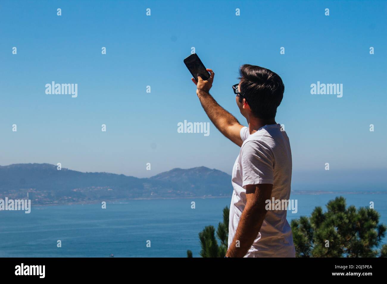 Young Spanish Caucasian man taking a selfie with his phone, outdoors on ...