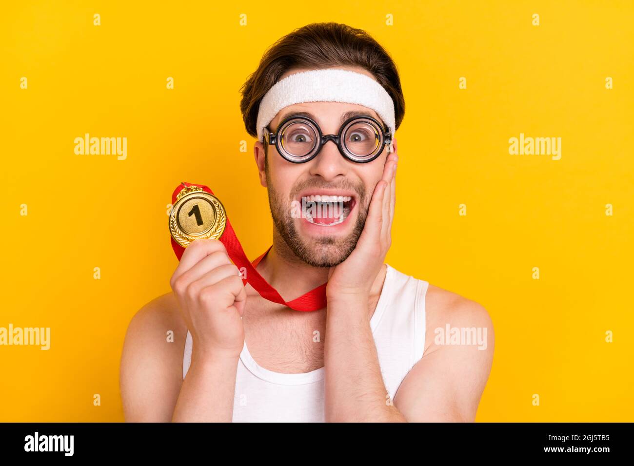 Portrait of handsome cheerful guy nerd leader holding golden medal ...