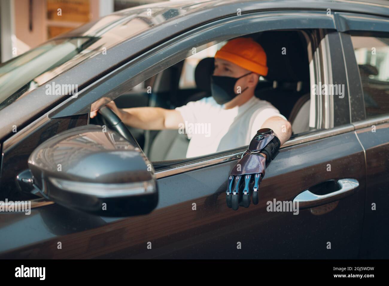 Young disabled man driver with artificial prosthetic hand driving ...