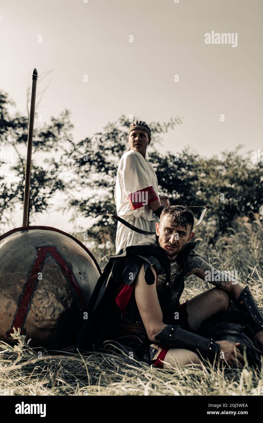 Ancient Spartan warrior in battle dress and woman archer rest among ...