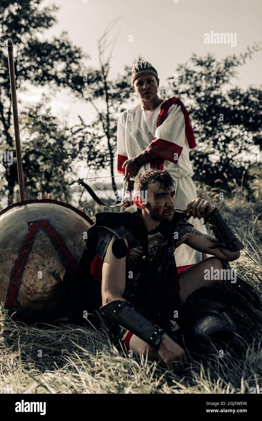 Ancient Spartan warrior in battle dress and woman archer rest among ...