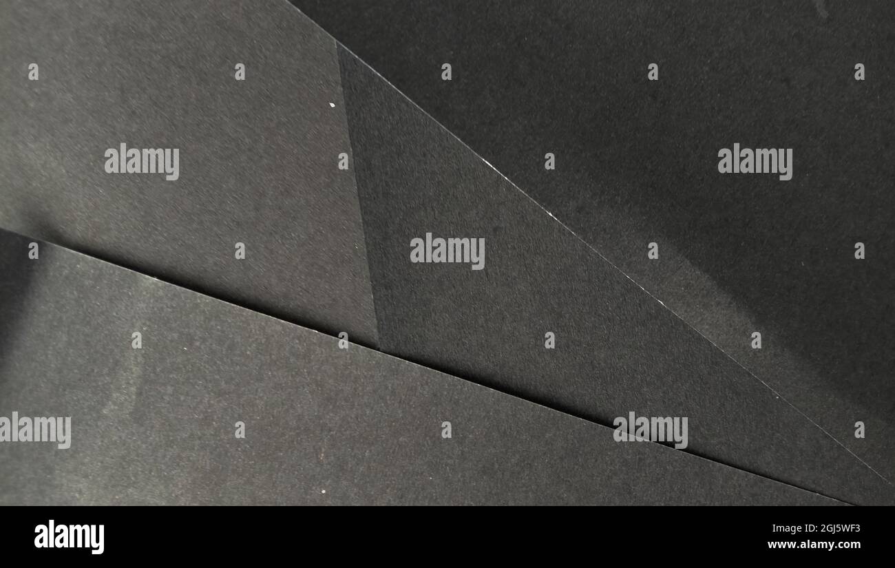 Closeup of black-colored papers on top of each other, black background ...