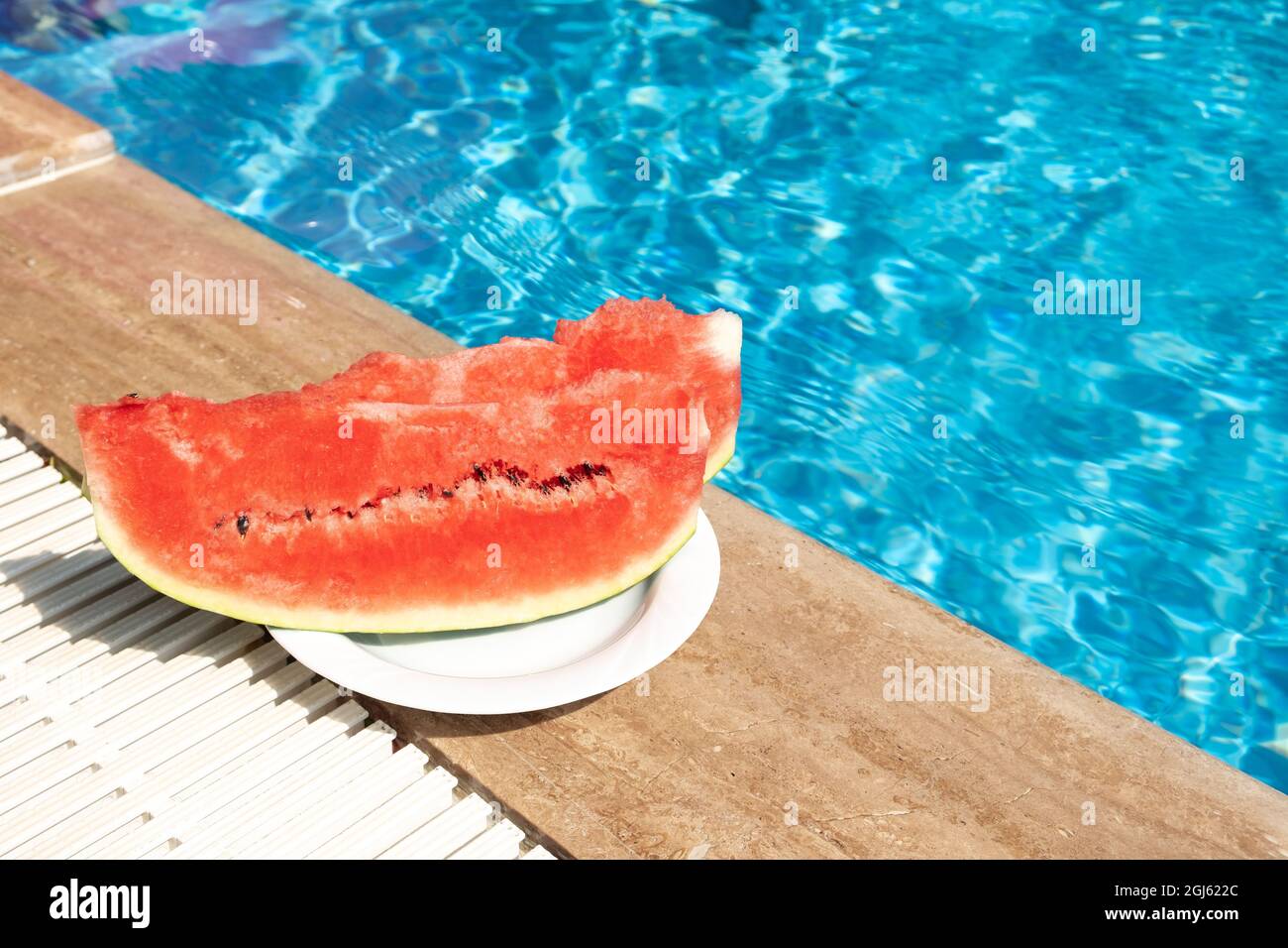 Fresh watermelon on border of swimming pool. Summer holiday tropical ...